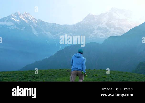 Person in outdoor gear gestures toward misty mountain ranges in the ...