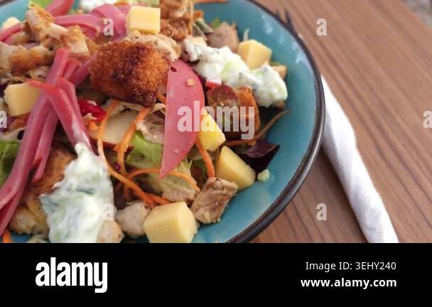Close-up of a fresh mixed salad with grilled chicken pieces, pickled ...