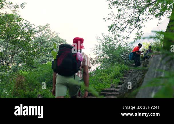 Group of hikers with backpacks walking along a steep path surrounded by ...
