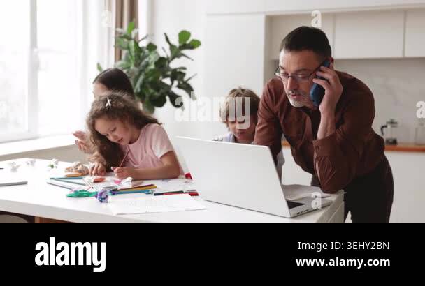 Man father using laptop, talking on phone, handling business tasks from ...