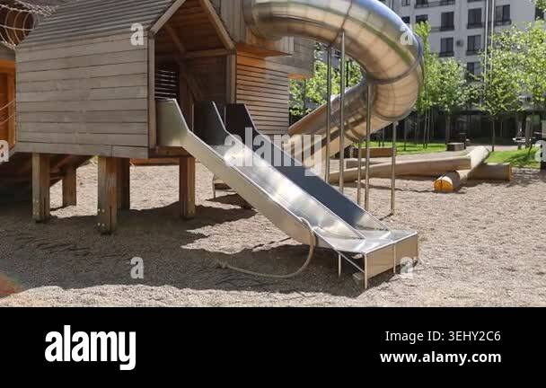 Shiny metal spiral slide in courtyard twisting stainless tube behind ...
