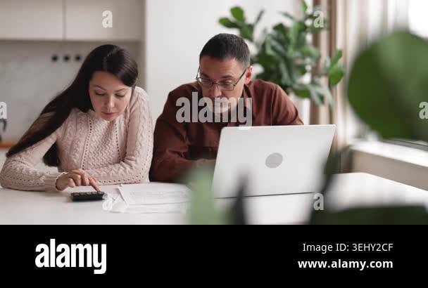 Couple sitting at kitchen table handling household finances, wife ...