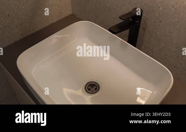 White sink closeup with black faucet, terrazzo wall backdrop, square ...