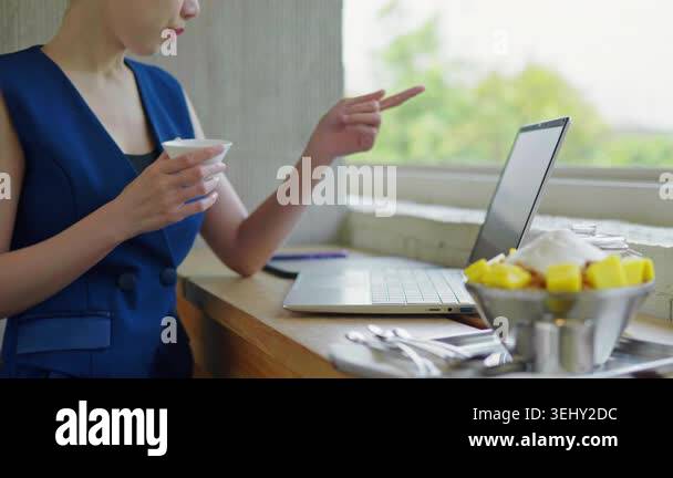 Businesswoman pointing at laptop while holding cup of coffee Stock ...