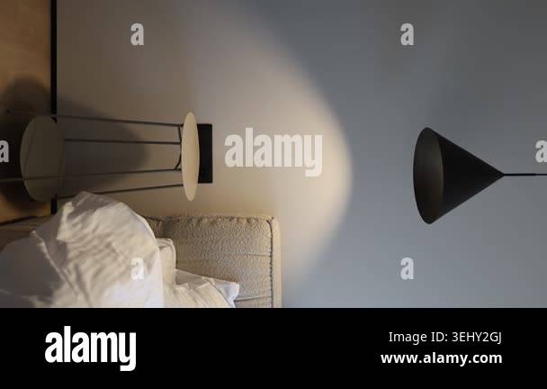Bedside lamp casting circular light pool on wall above textured ...