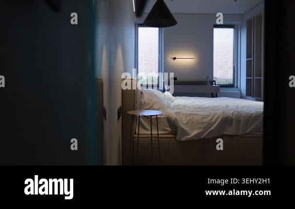 City view from bed at sunrise with rumpled sheets and bedside stool ...