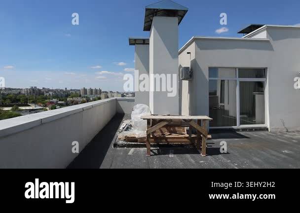 Rooftop terrace under clear blue sky, white building facade with ...