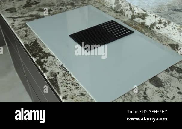 Modern glass cooktop on granite countertop, black slatted trivet ...