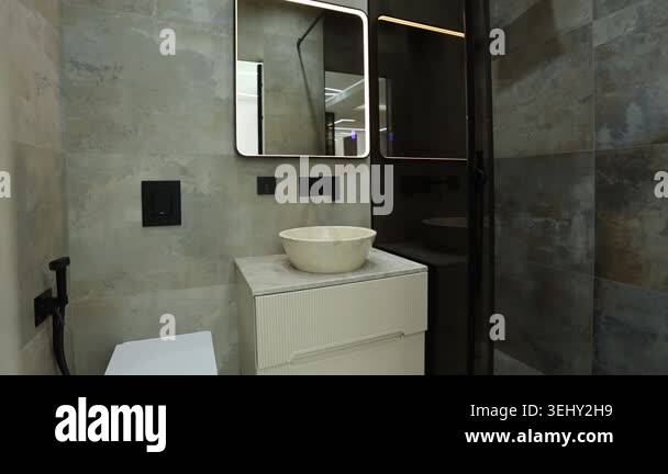 Compact modern bathroom with vessel sink and illuminated mirror, dark ...