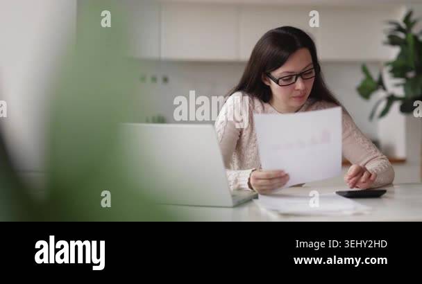 Focused Caucasian business woman calculates finances, reviewing ...