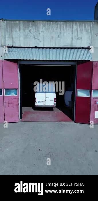 White van sits inside a large, open industrial garage. The garage door ...