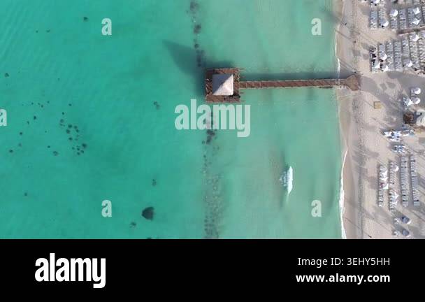 Drone view of a wooden pier with a brown roof extending into the ...