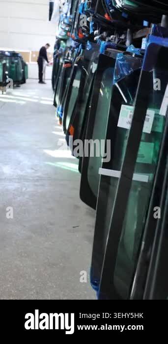 Rows of car windows stand upright in a warehouse. Person walks slowly ...