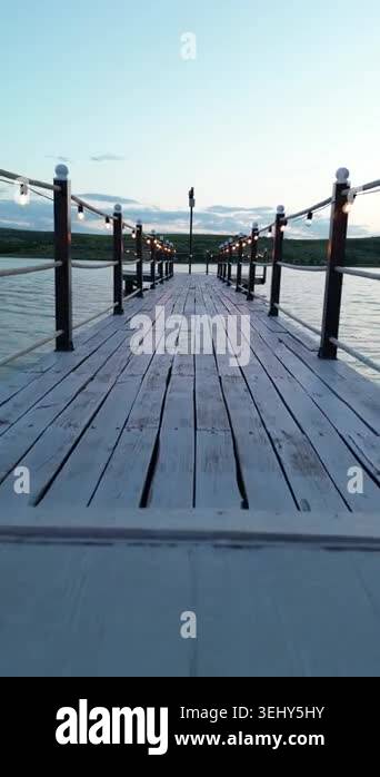 Wooden Pier Leading Into Calm Lake At Dusk, Lanterns Lining Railing ...