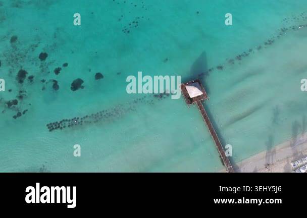 Aerial shot of a wooden pier with a brown roof extending into the ...