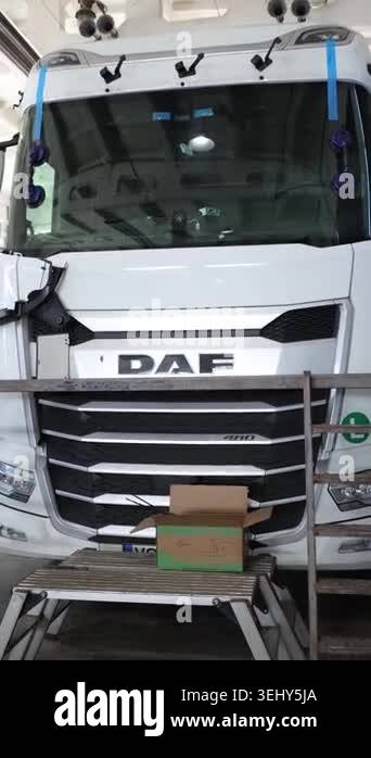 Large white truck inside workshop, undergoing maintenance. Metal ladder ...