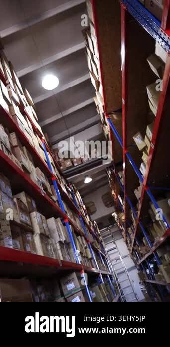 High-angle view of warehouse aisles filled with stacked boxes. Red and ...