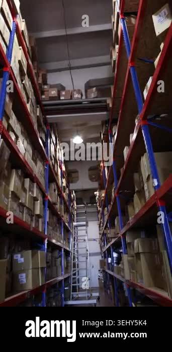 Warehouse aisles packed with boxes on red and blue shelves. Metal ...