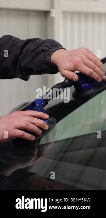 Person uses squeegee to clean car windshield. Hands move steadily ...