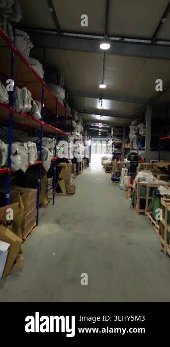 Warehouse interior with tall shelves holding bags and crates. Long ...