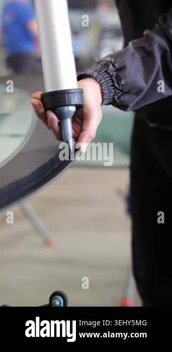 Hand holds tool applying sealant to curved glass surface. Worker ...