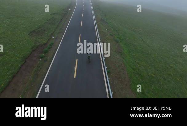 Aerial footage of riding road bike in the beautiful grassland mountain ...