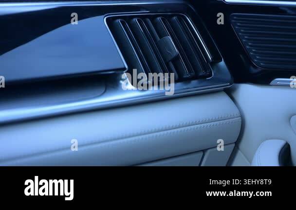 Inside a luxurious car, soft beige leather contrasts with glossy black ...