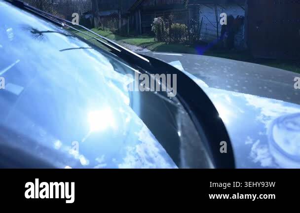 Wipers wipe the windshield of an SUV. Sunlight sparkles like diamonds ...