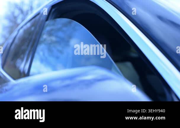 Lowering a car door window. A modern car window reflects clear blue ...