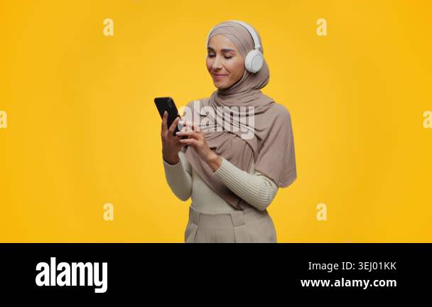 A young woman listens to music on her smartphone while wearing ...