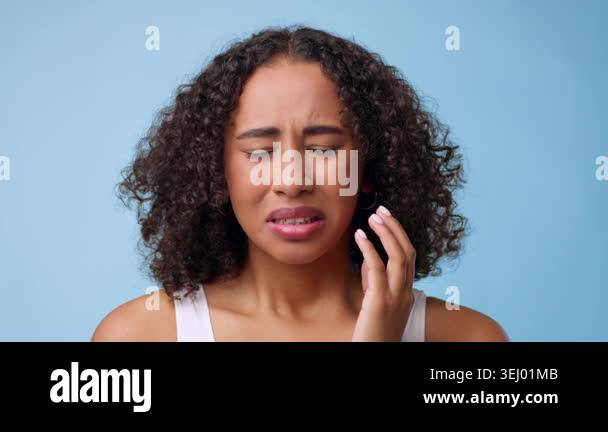 A woman with curly hair is seen with a pained expression on her face ...