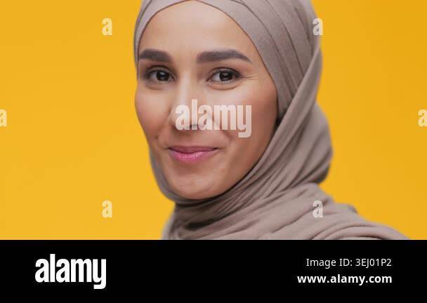 A woman wearing a headscarf smiles while facing the camera. The bright ...