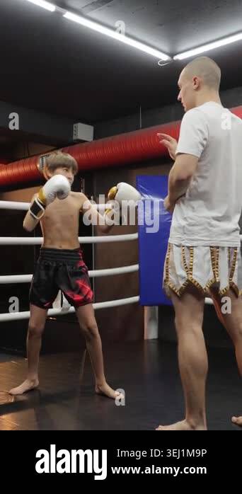 Male boxing coach teaching a young boy how to punch correctly in a ...