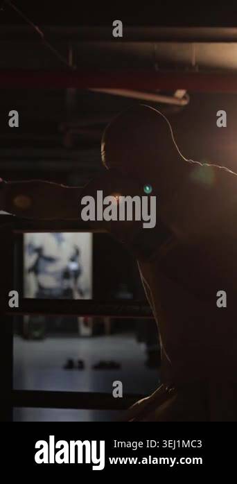 Silhouette of a boxer intensely training with focus pads inside a dark ...