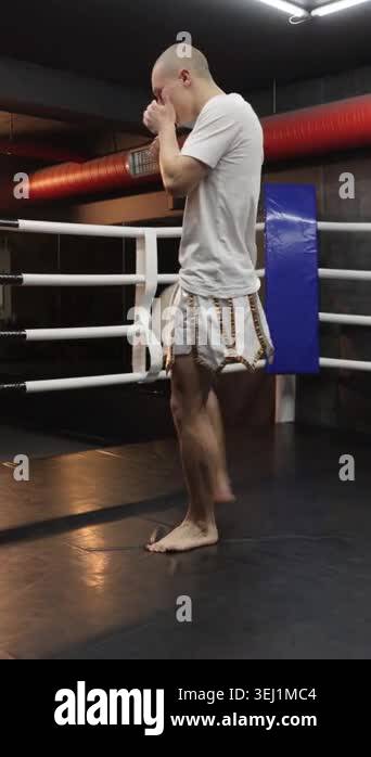 Muscular male fighter in shorts practicing kicks and punches alone ...