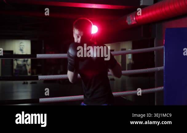 Young athletic man shadowboxing in a boxing ring, preparing for a fight ...