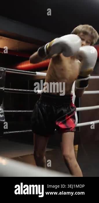 Focused young boy in boxing gloves practicing his punches and footwork ...