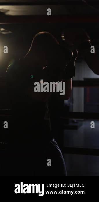 Male and female boxer silhouettes training together in a dark ...