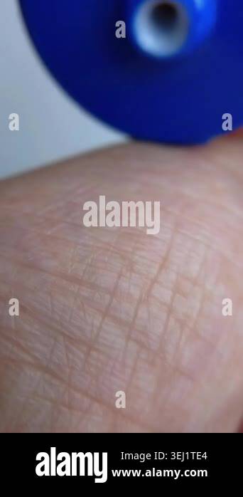 Pouring white cream from blue product packaging onto hand skin. Natural ...