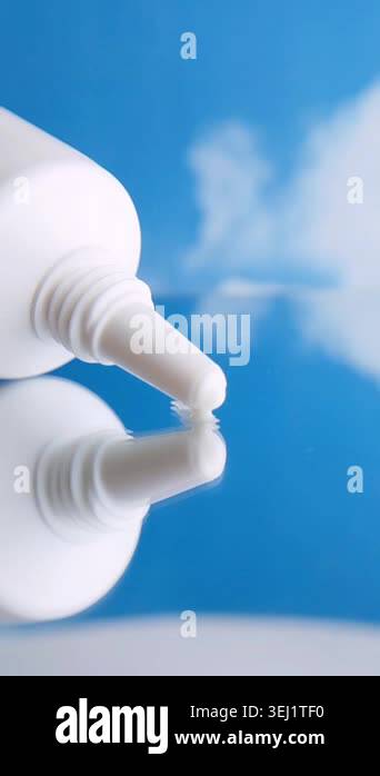 White cream slowly dispensing from white product packaging onto ...