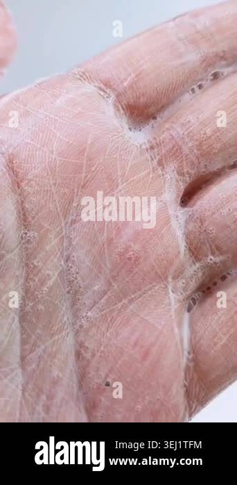 Rubbing palm slowly with cleansing soap. Close up view of hand washing ...