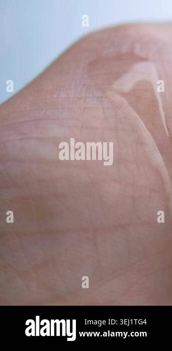 Dropping clear liquid cleansing soap onto the palm of a hand. Close up ...