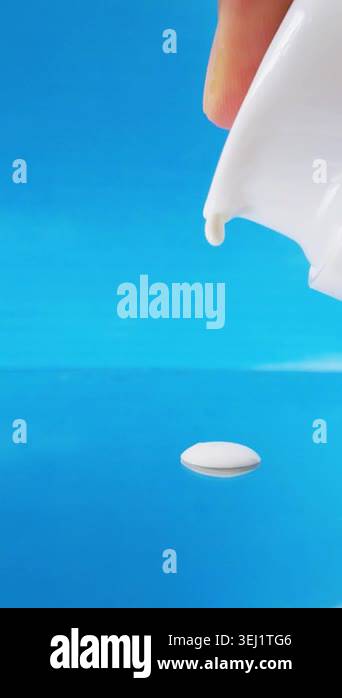 White beauty cream dripping onto reflective glass surface with blue ...