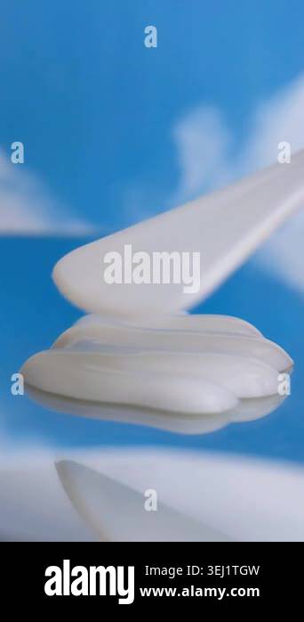Spreading white cream on reflective glass surface using a tool. Blue ...