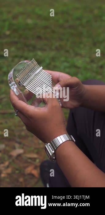 A close-up of an Asian man's hands playing an acoustic kalimba in a ...