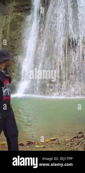 4K footage of a solo adventurer visiting a pristine waterfall in the ...