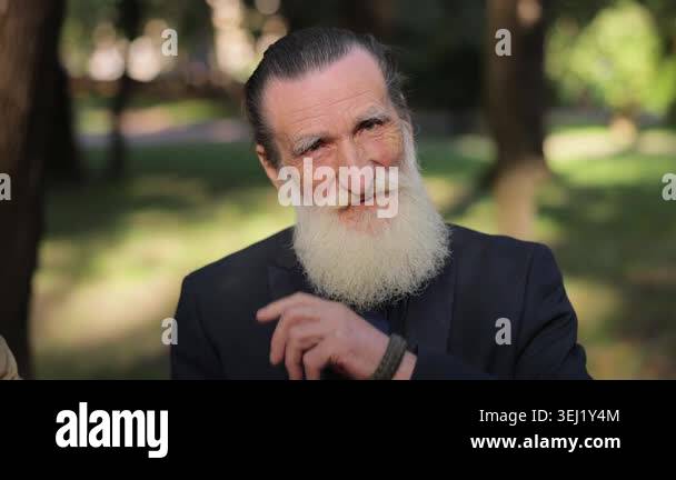 Cheerful senior man with a long white beard smiling and looking at the ...