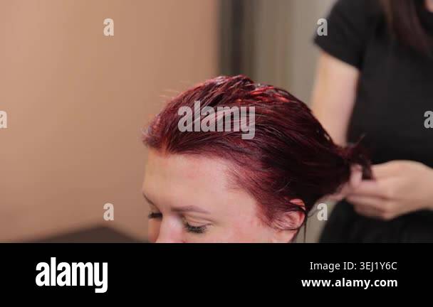 Professional hairstylist working on a female client with vibrant red ...