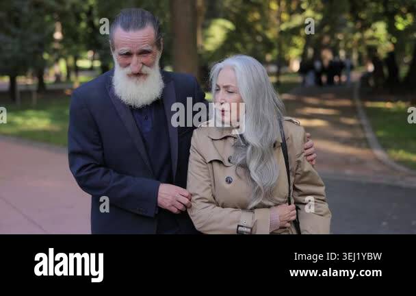Loving senior couple talking and walking arm in arm through a beautiful ...