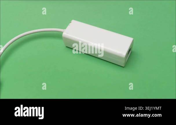 White USB to RJ45 LAN network adapter converter lying on a solid green ...